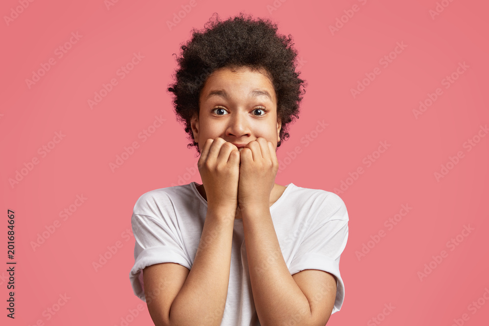 African boy feels anxious and nervous, bites finger nails, worries ...