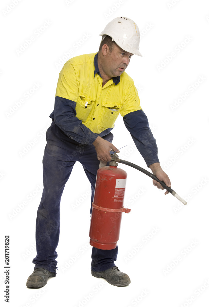 An industrial worker using a fire extinguisher to put a fire out ...