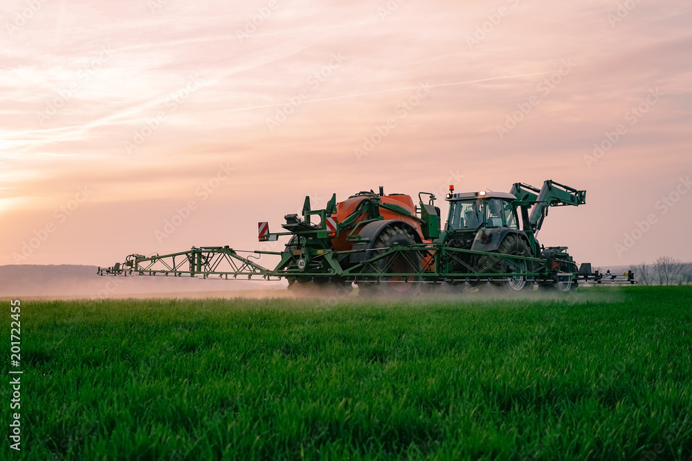 Pflanzenschutz in der Landwirtschaft, Landwirt spritzt sein Getreide beim Sonnenuntergang ...