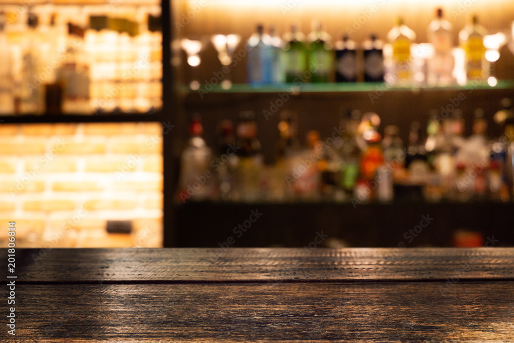 Empty dark wooden bar counter with blur background bottles of ...