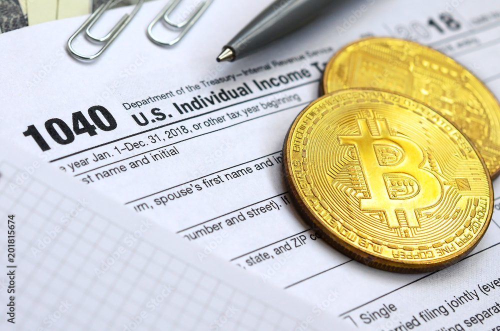 The pen, bitcoins and dollar bills is lies on the tax form 1040 U.S ...