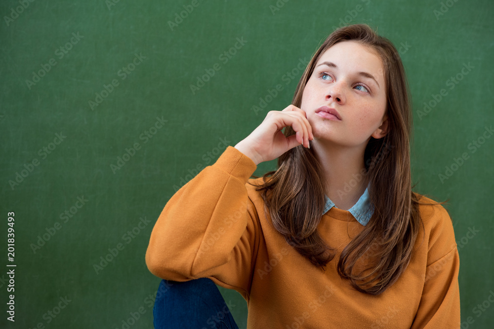 Student thinking and leaning against green chalkboard background ...