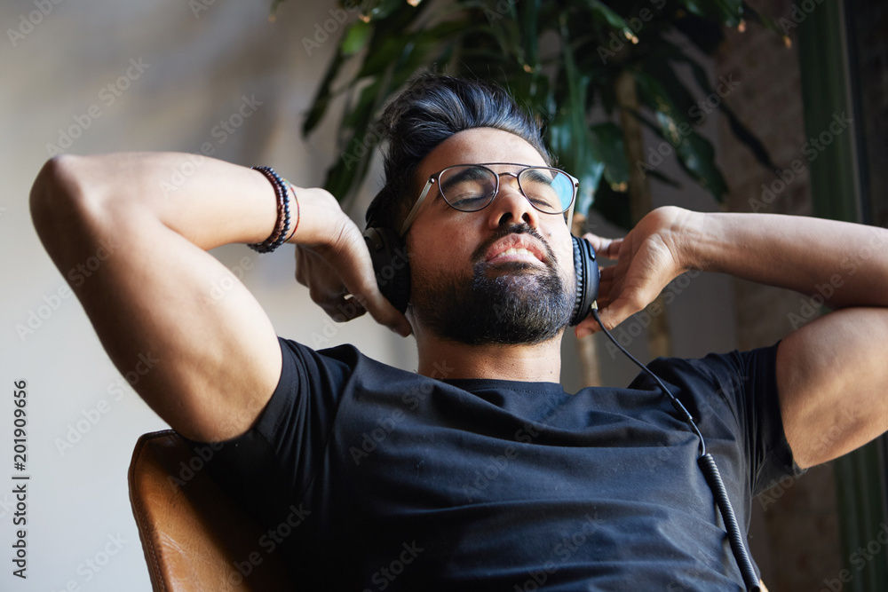 Handsome bearded man in headphones listening to music at home. Relaxing ...