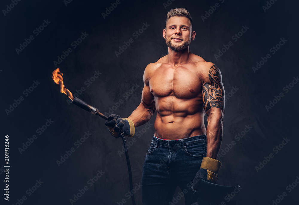 Brutal tattoed male welder with a stylish haircut and beard, with ...