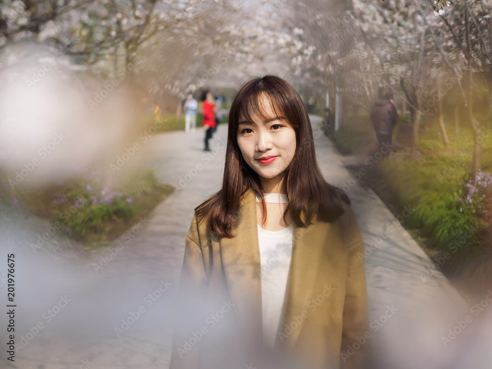 Outdoor portrait of beautiful young Chinese girl smiling among blossom ...