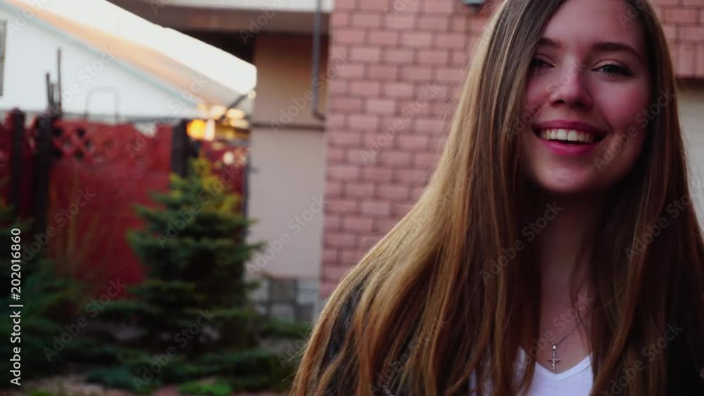 Pretty smiling girl passing with close up face near house in slow ...