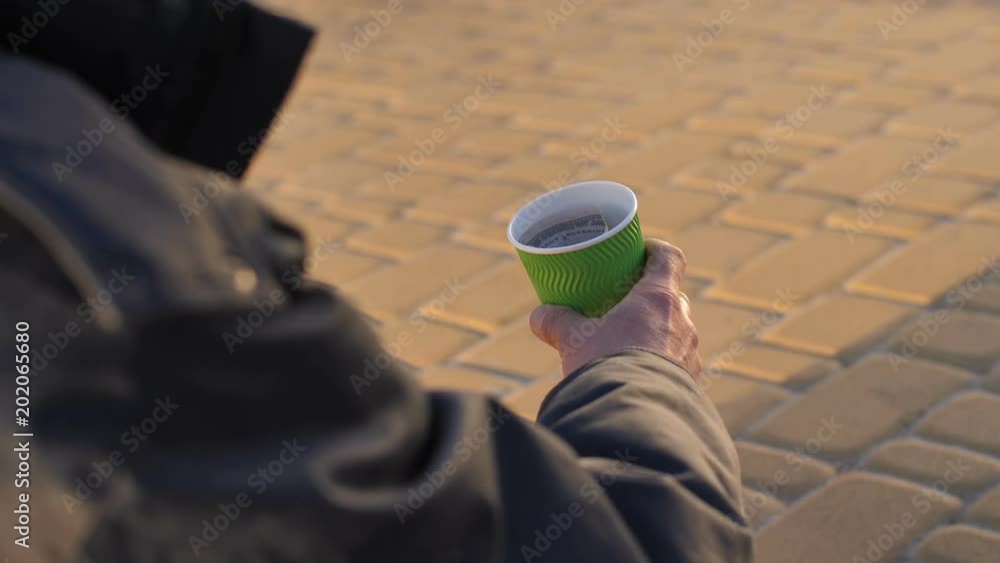 Close-up homeless beggar male's hand holding paper cup. Man begging for ...