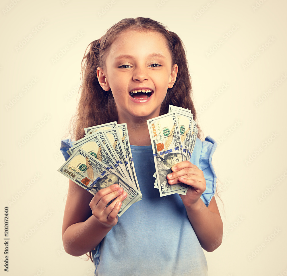 Happy laughing rich kid girl holding money in the hand. Vintage toned ...