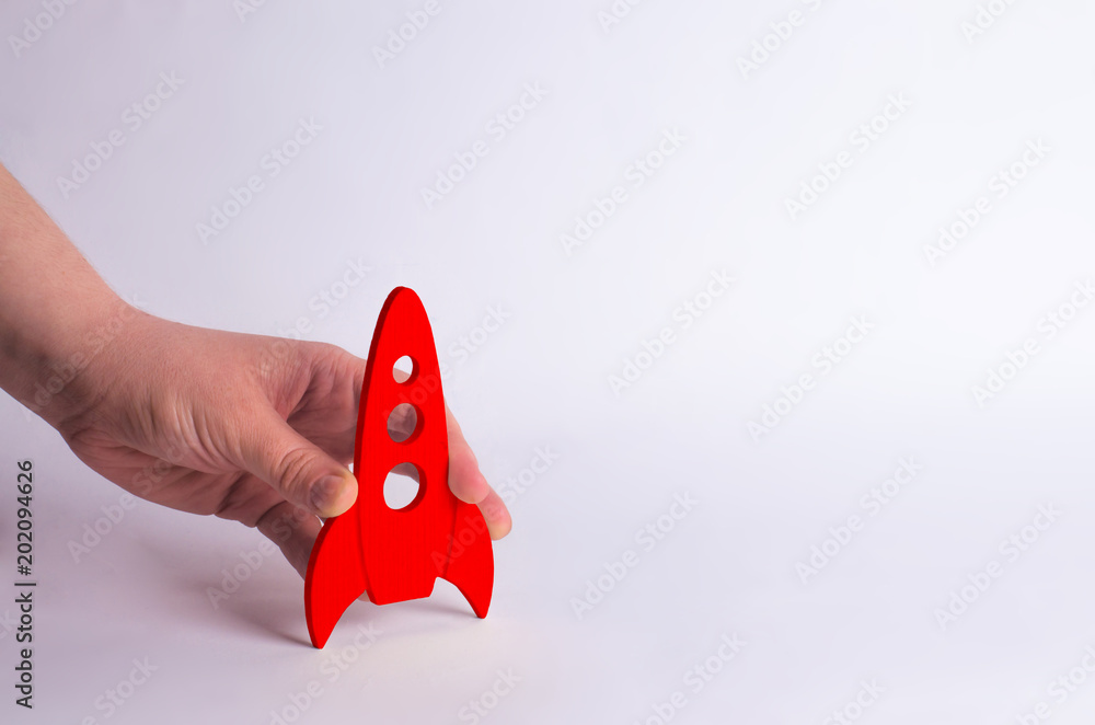 Wooden red rocket in hand on a white background. A man is playing with ...