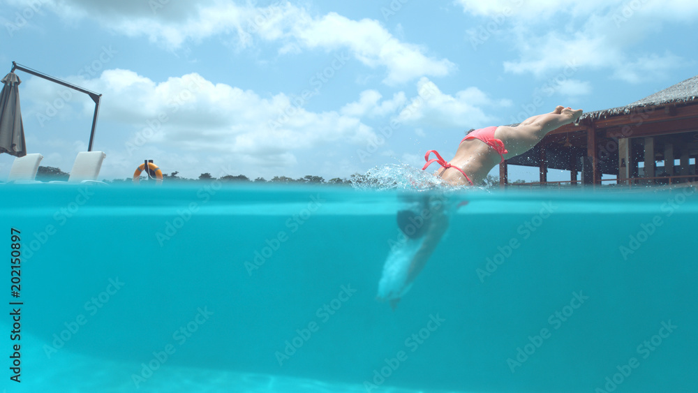 HALF UNDERWATER: Playful young female traveler jumps head first into ...