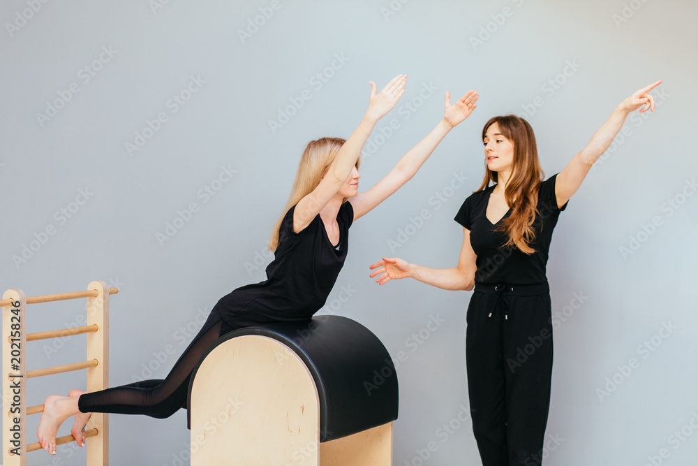 Young blond girl doing swan pilates exercises on ladder barrel with ...