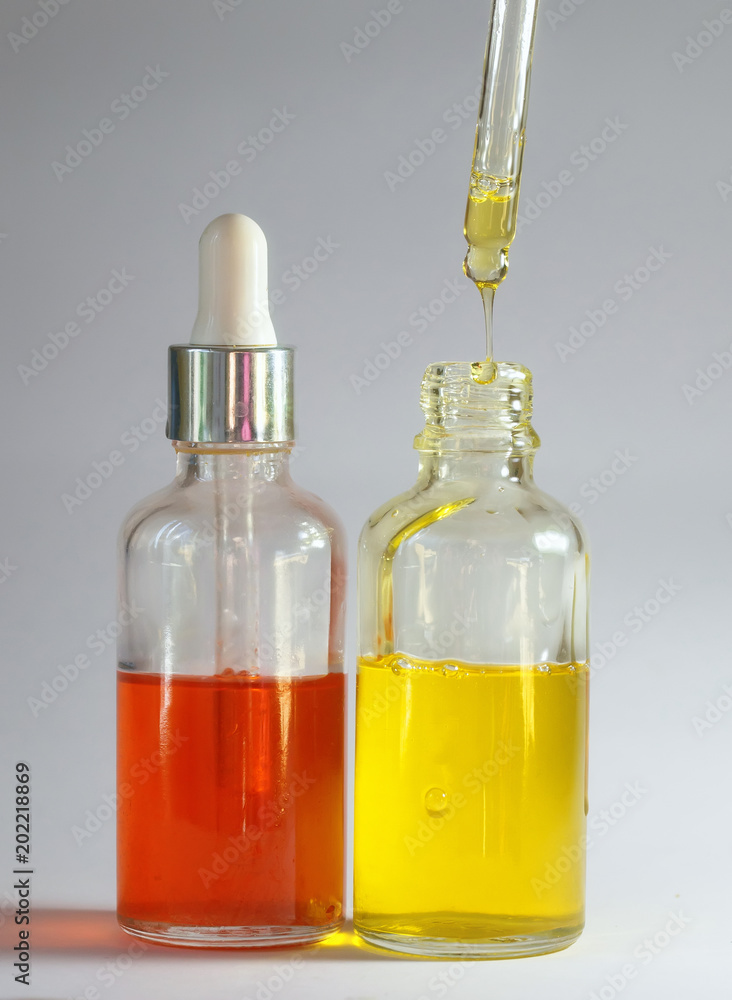 a drop of bright useful cosmetic oil drops from a transparent pipette ...