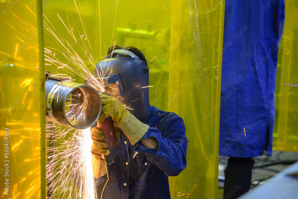 The skill worker use hand grinder machine grinding the steel pipe.The ...