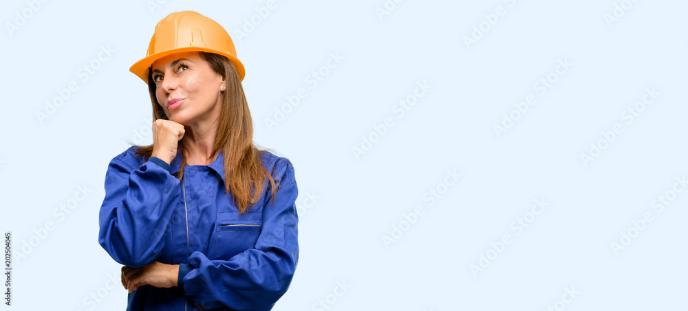 Engineer construction worker woman thinking and looking up expressing ...