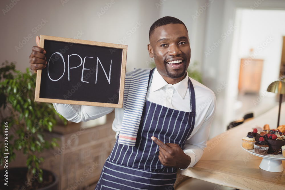 Smiling waiter showing chalkboard with open sign Stock Photo | Adobe Stock