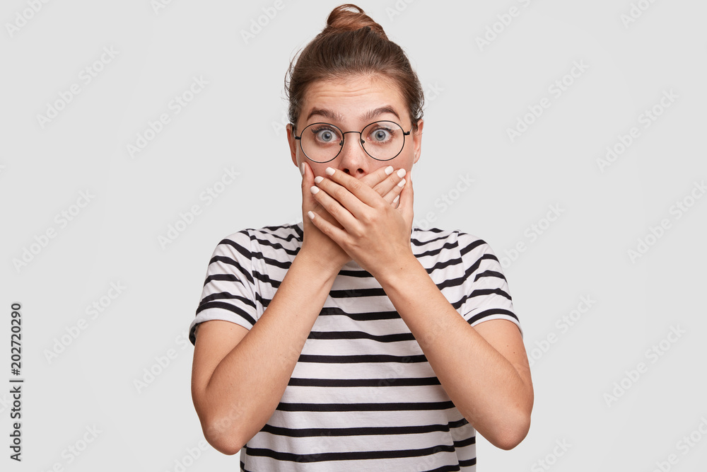 Emotional scared lovely young female covers mouth with fear, finds out ...