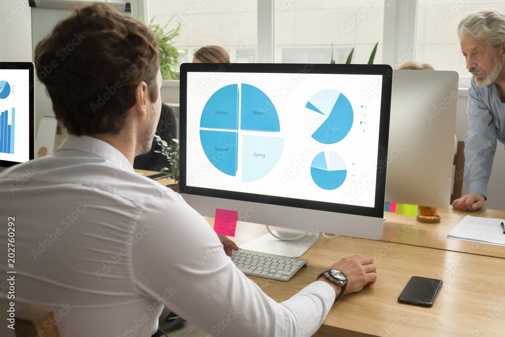 Young man employee using computer application with charts on screen ...
