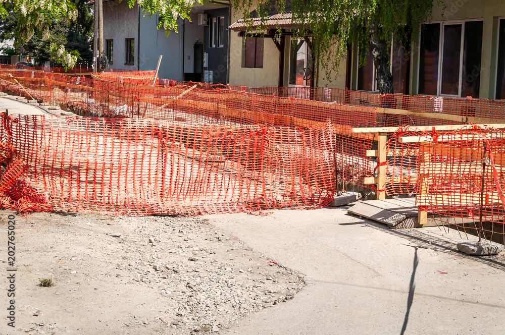 Construction site orange safety net fence as barrier over the trench on ...