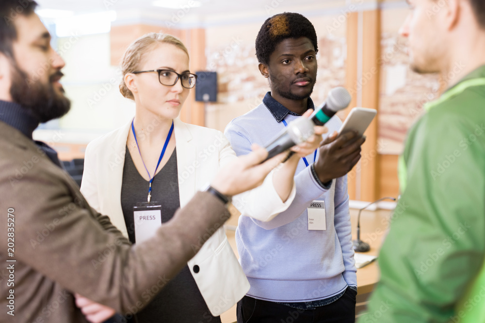 Group of journalists asking questions at press conference taking ...