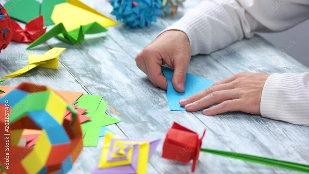Man at origami art workshop. Set of origami figures and male hands ...