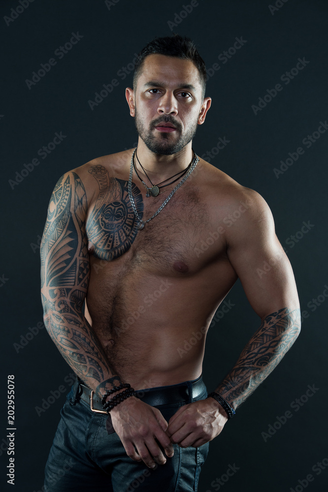Bearded man with tattooed body. Macho with sexy bare torso in jeans ...