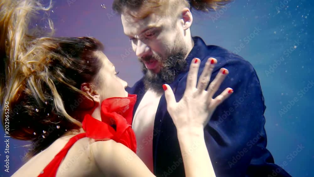 passionate loving couple are floating underwater dressed in clothes ...