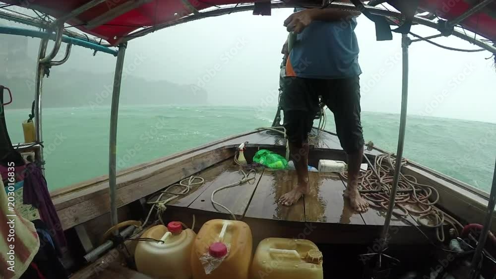 CLOSE UP: Dripping wet Thai boat taxi driver steers his wooden boat ...