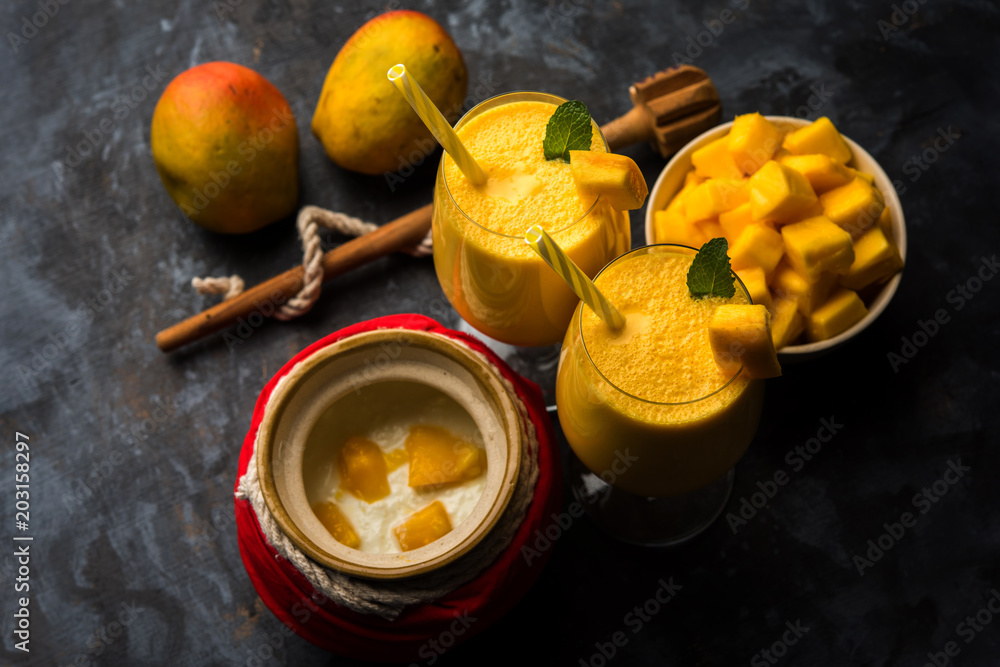 Mango Lassi or smoothie in big glass or small bottles with curd, cut ...