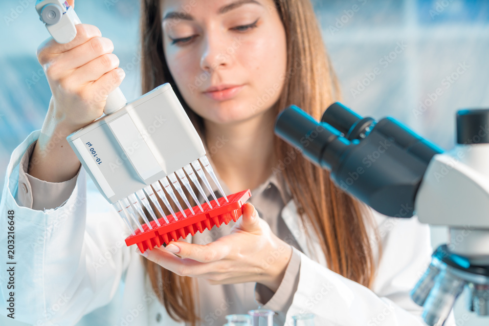 student woman with multi pipette and other PCR items in microbiological ...