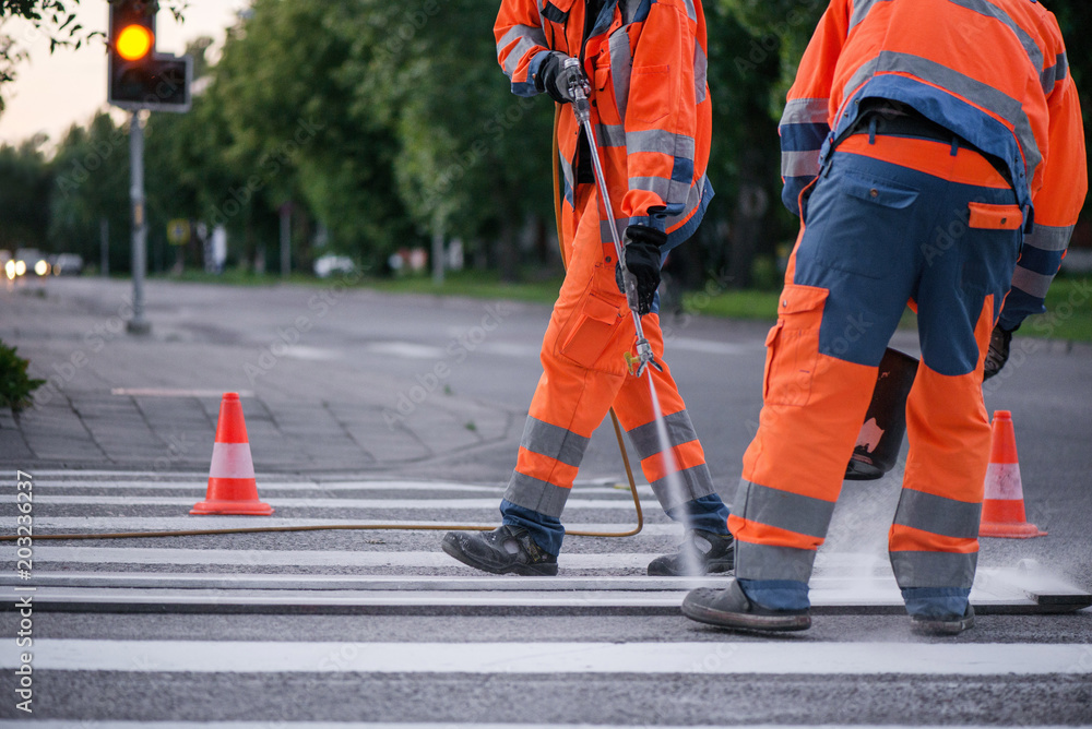Traffic line painting. Workers are painting white street lines on ...