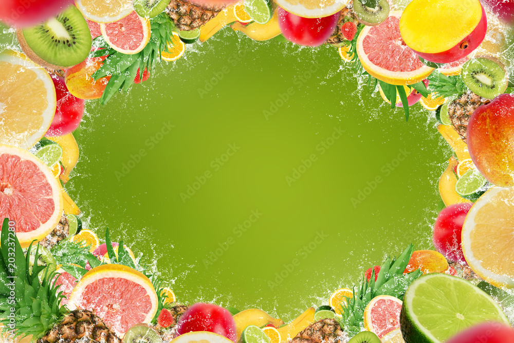 Frame of tropical fruits with water splash on green background, empty ...