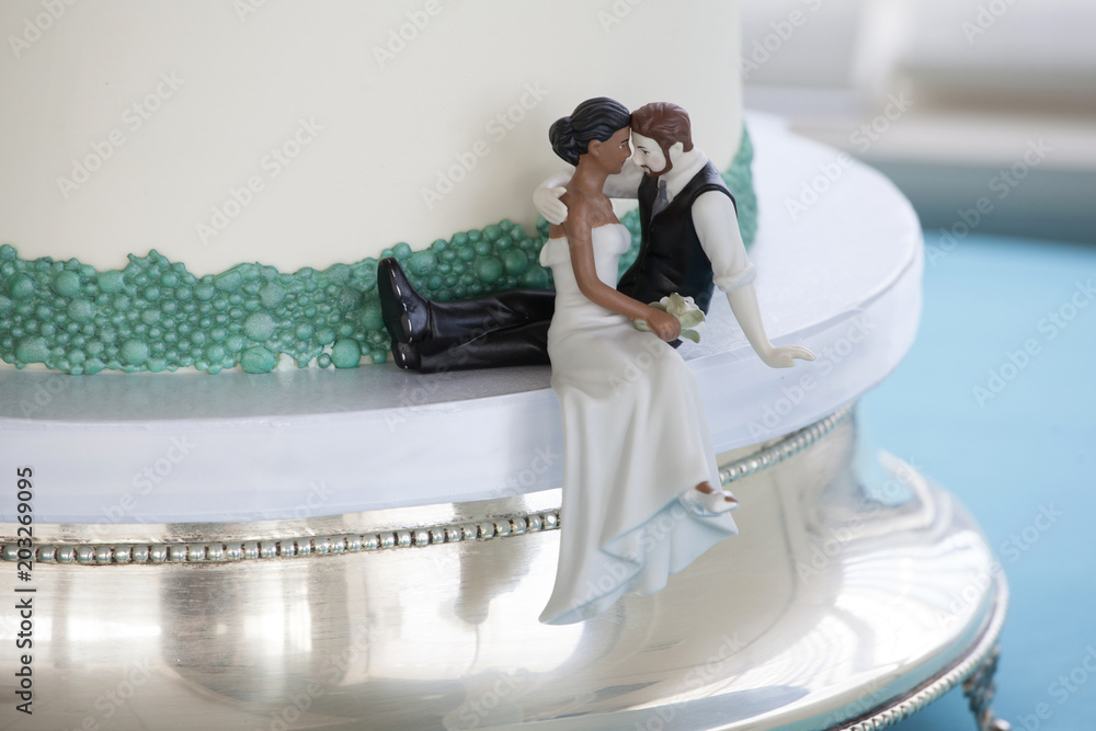 Cake topper on wedding cake featuring interracial couple. Stock Photo | Adobe Stock
