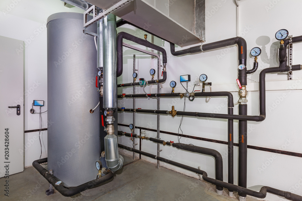The interior of an industrial boiler house with a multitude of pipes ...