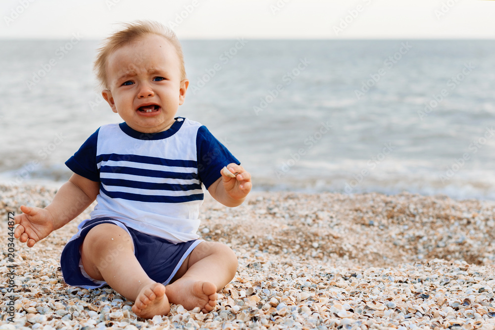 Crying little boy on the sea shore. Portrait of unhappy sad child with ...
