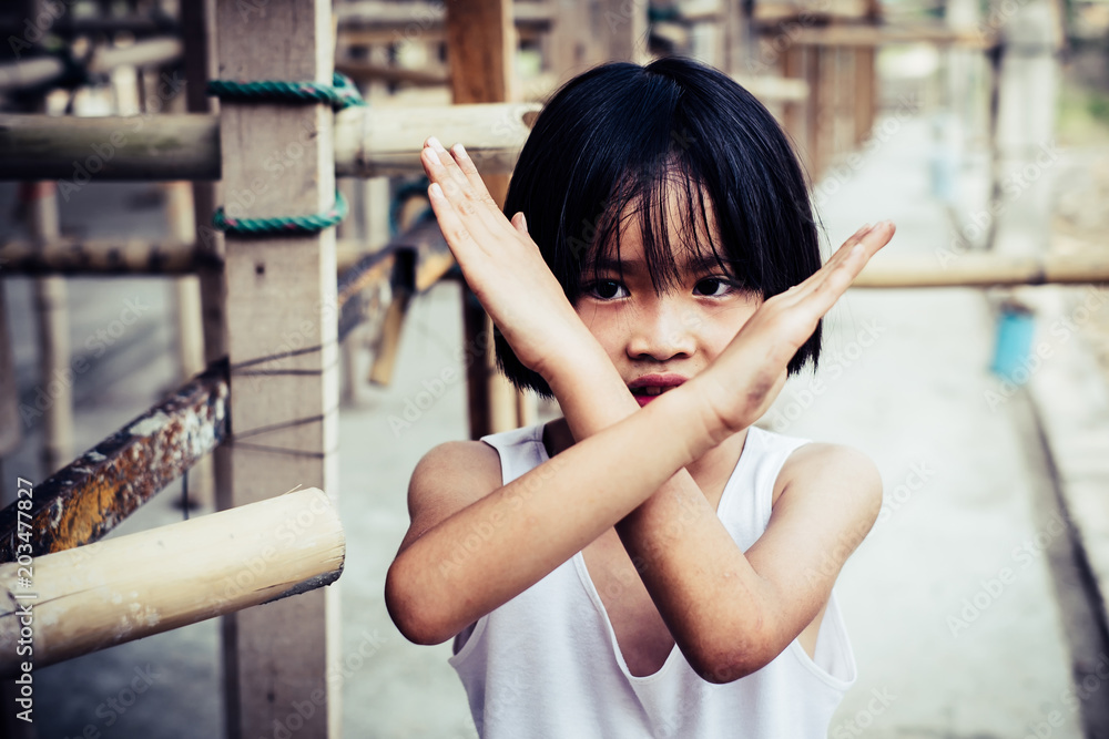 Little girl labor making X shape for Extreme with his hands. World Day Against Child Labour ...