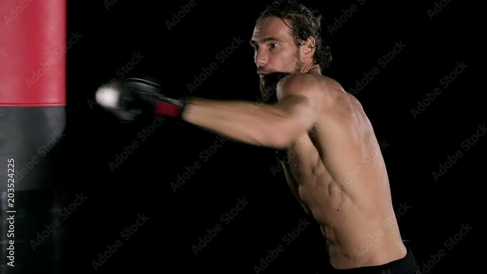 Slow motion of boxer punch a punching bag. Young white man with beard ...