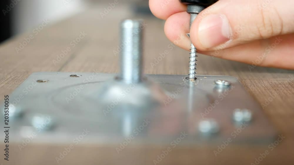 Slow motion footage of monting a screw in the table through a metal ...