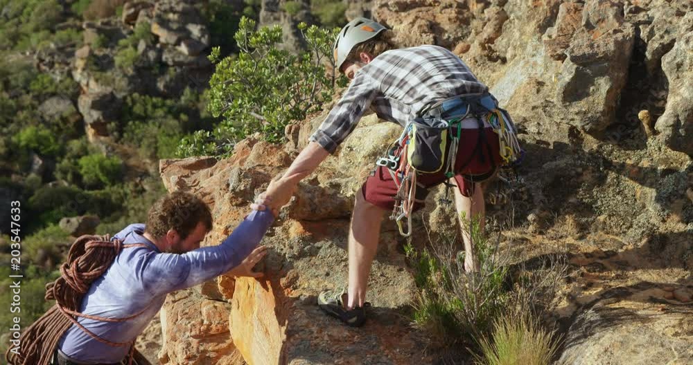 Man helping his friend to climb a cliff Stock Video | Adobe Stock