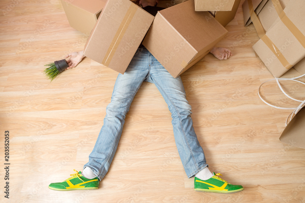 Photo of man in jeans and sneakers lying under cardboard boxes Stock ...