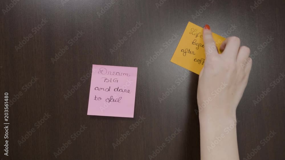 Female hands with red nails sticking various colored post it notes with ...