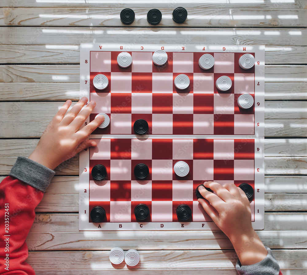 The child plays checkers. Children's hands on a checkerboard. Play ...