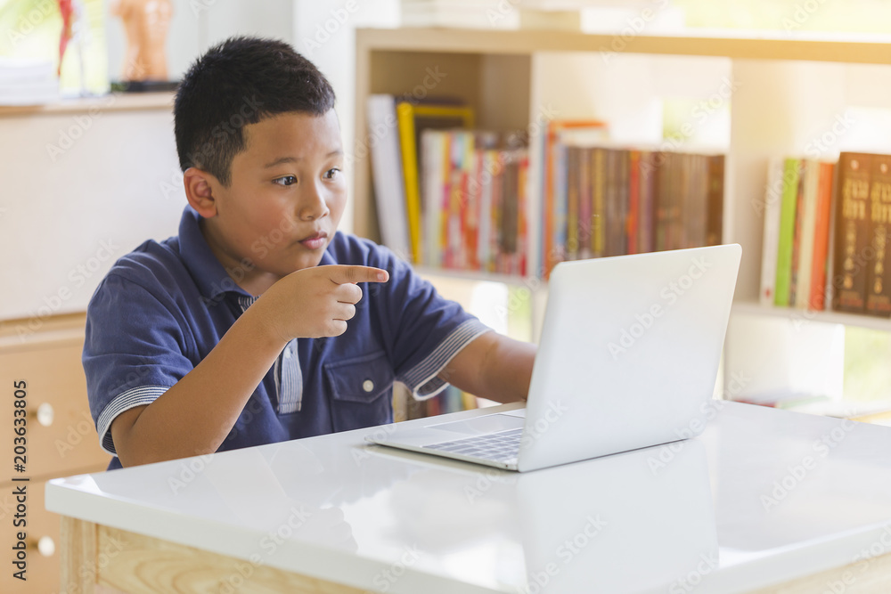 Excited child reading online laptop computer content at library. Asian ...