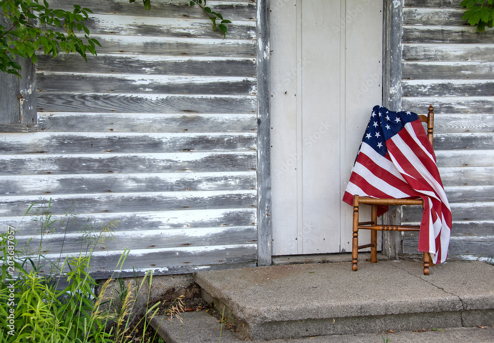 American flag draped over old wooden chair by rustic house door Stock ...