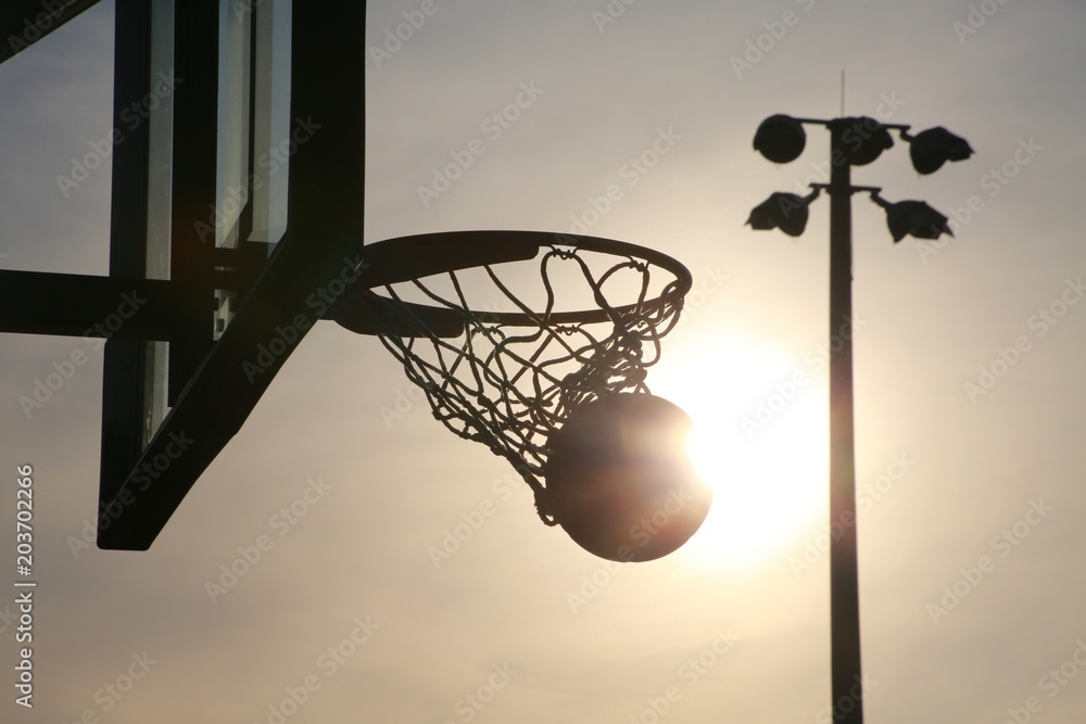 Basketball Going into Hoop Outdoors Late in the Afternoon in Silhouette ...