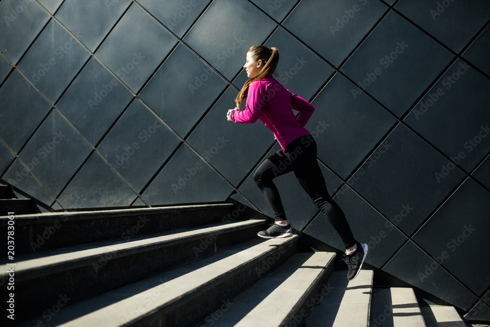 Urban run. Female athlete running fast up the stairs. staircase workout ...