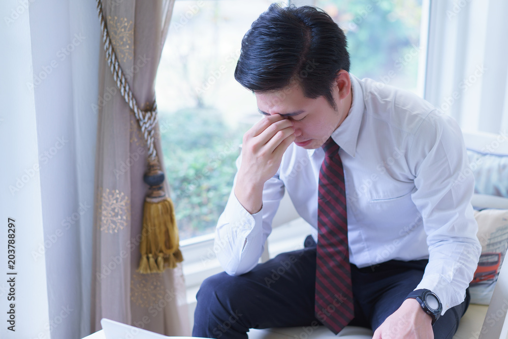 Stressed asian young businessman holding head with hands looking down ...
