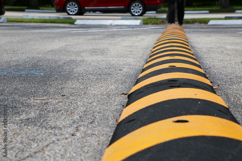 Yellow and Black Striped Speed Bump with Nails Visible in Parking Lot ...