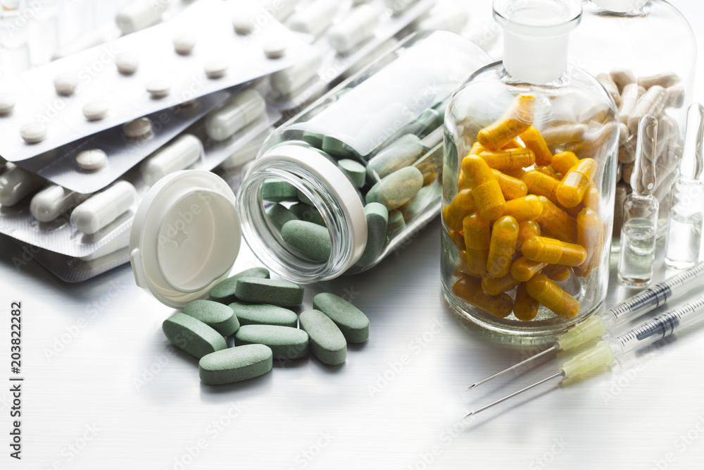 Medicines in tablets, capsules and injections on a metal table as a ...