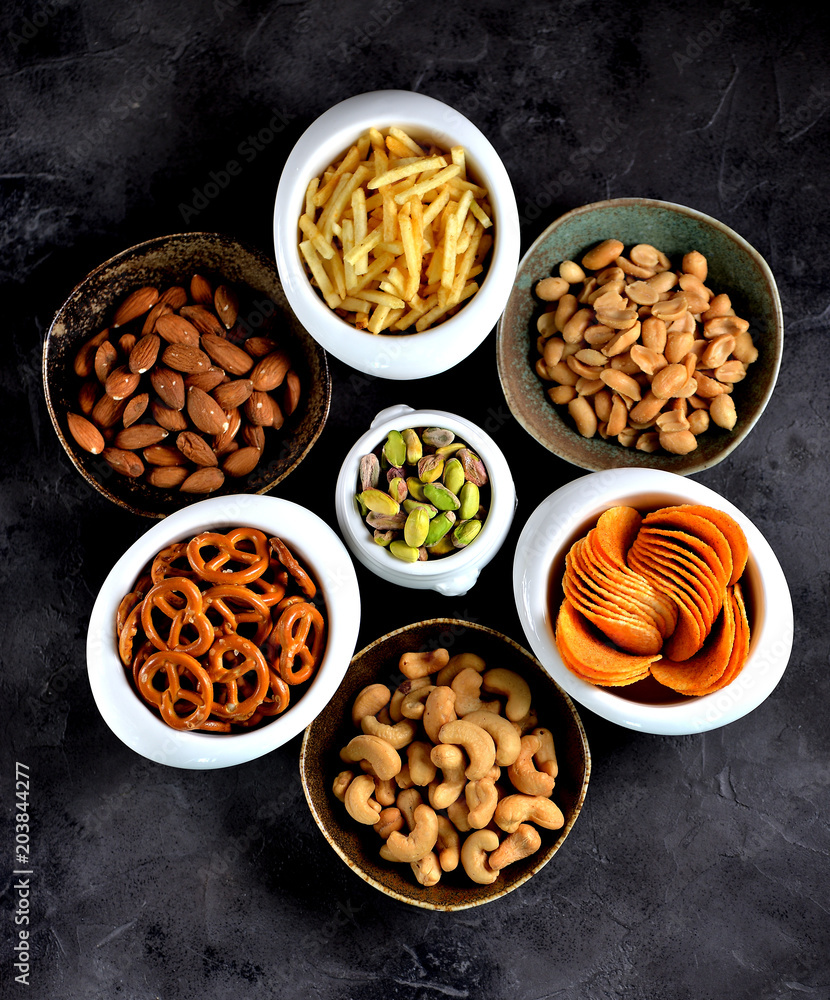 Different kinds of snacks - chips, salted peanuts, cashews, almonds and ...
