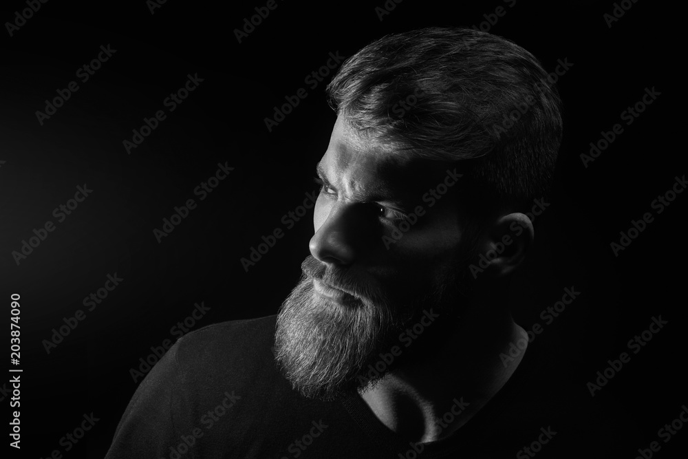 Black and white portrait of puzzled young man looking down over black ...